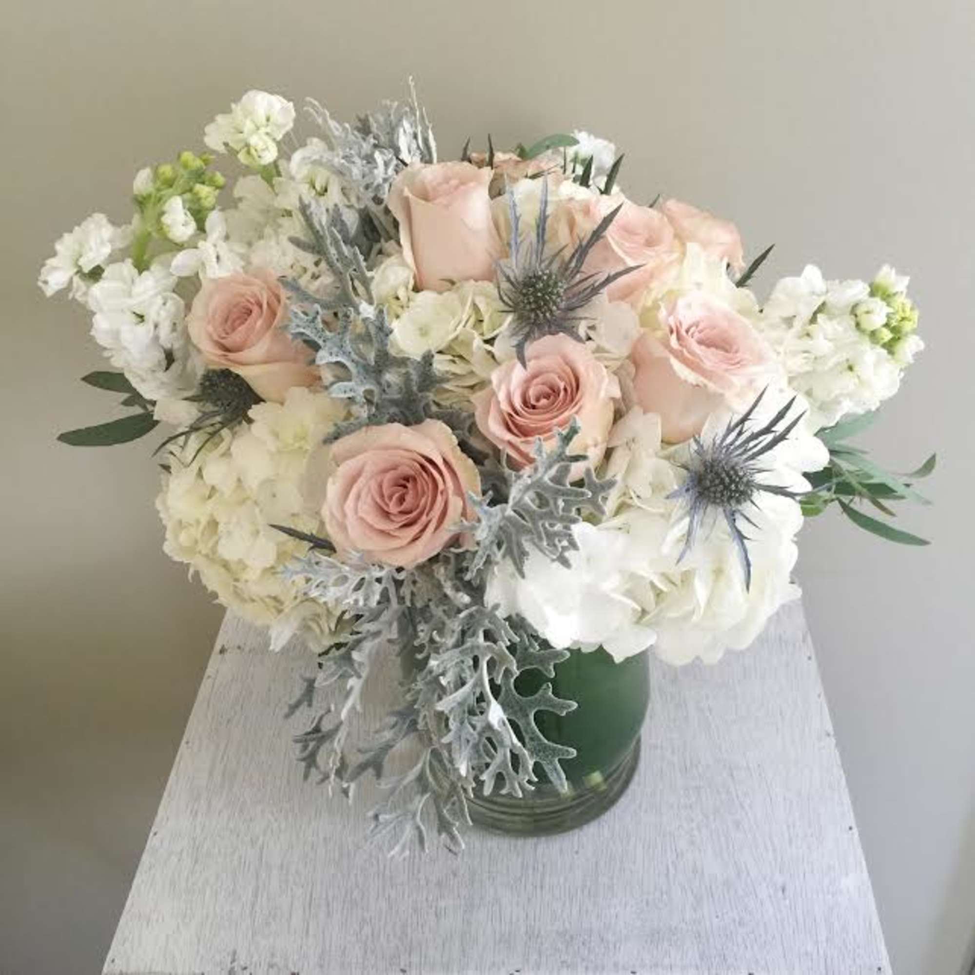 Tattershall A romantic almost shabby chic arrangement of White Stock Hydrangea Blush Quicksand Roses Dusty Miller and Thistle. in Valley Forge PA Bloomsbury Floral Design