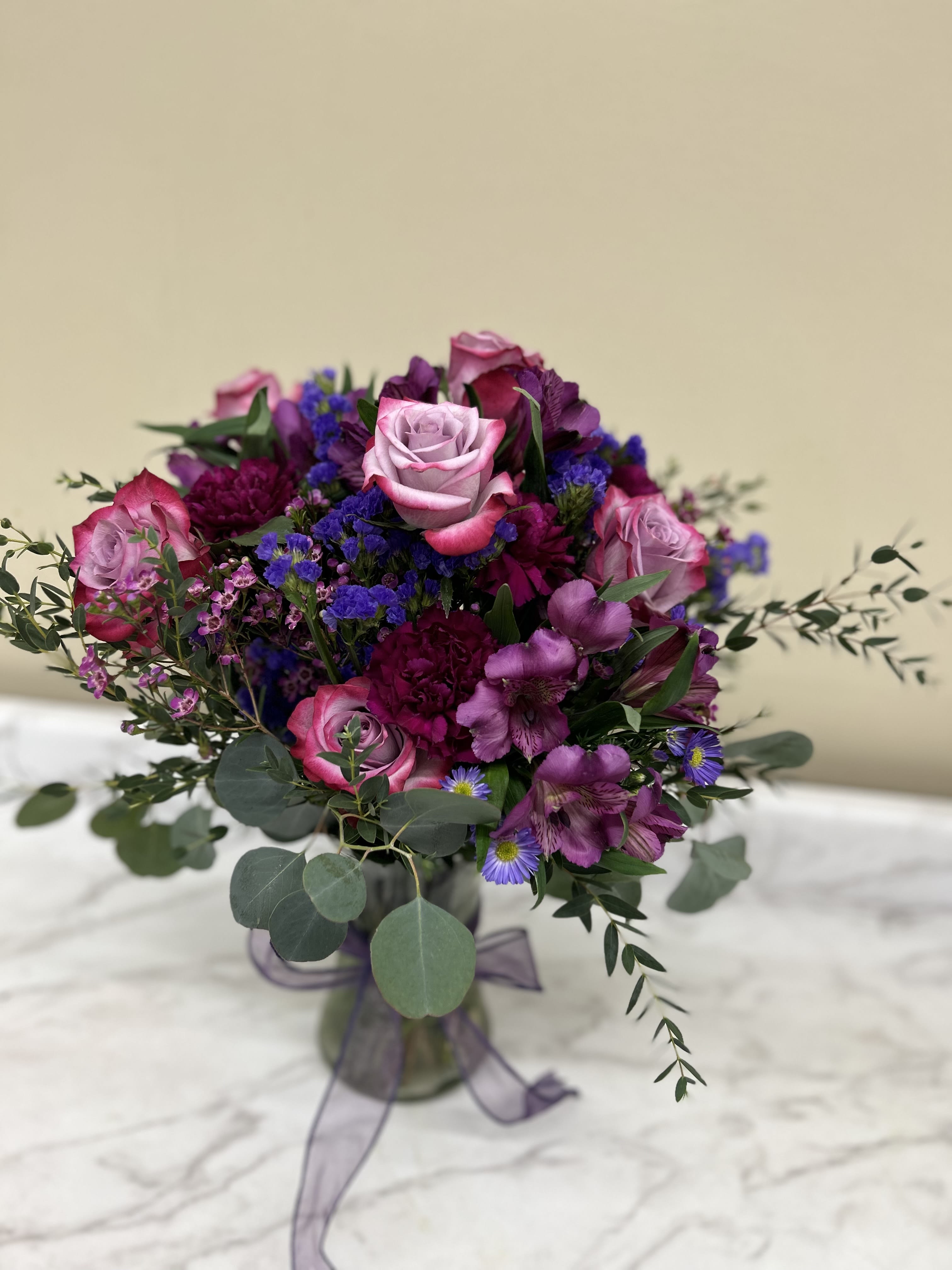 Purple status, wax, alstroemeria roses, aster, and other greenery in ...